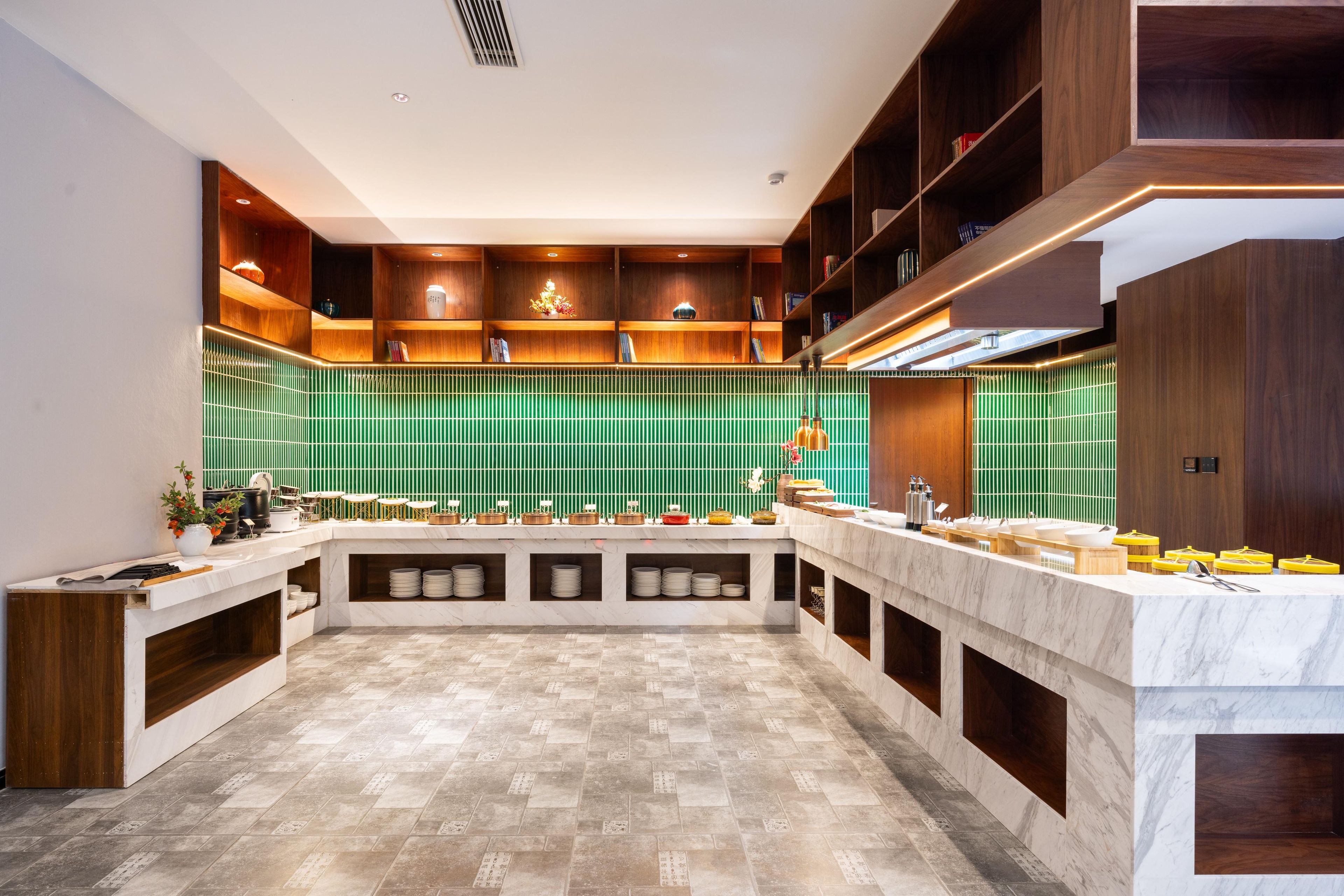 Cozinha moderna com ilha central, prateleiras embutidas e painel de fundo verde.