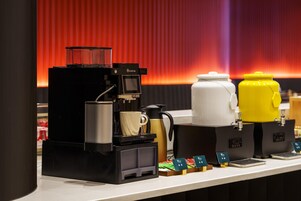 Um espaço com estação de café, máquina de café, vaporizador de leite e dispensador de água.