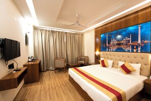 Quarto de hotel com uma cama grande, televisão de tela plana, escrivaninha e uma cadeira.