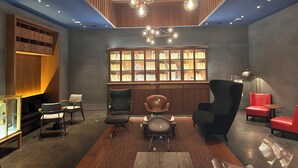 Um hall moderno com teto de madeira, uma vitrine de vidro com livros e diversas áreas de estar.