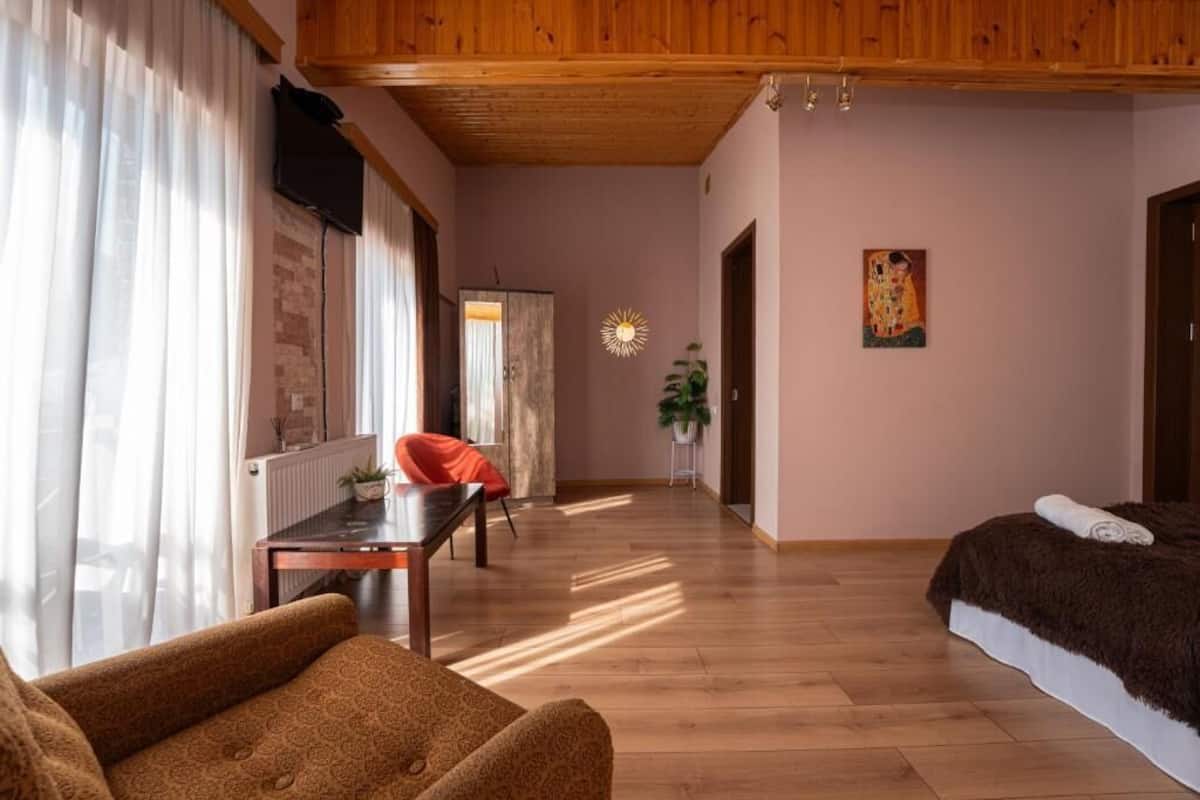 Um quarto com cama, sofá, mesa de jantar e uma cadeira vermelha.