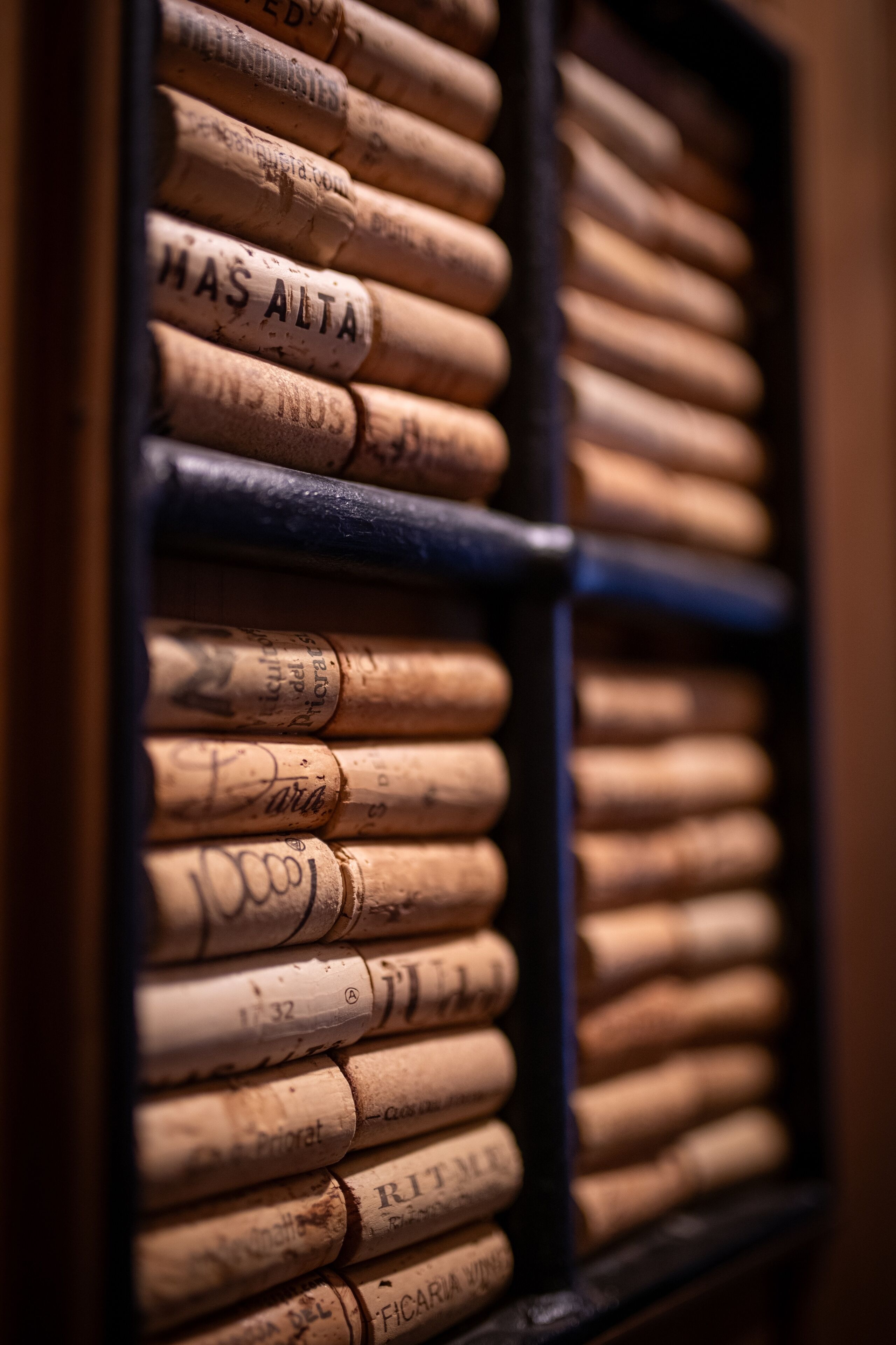 Um close-up de cortiças de rolha de vinho empilhadas em um armário escuro.