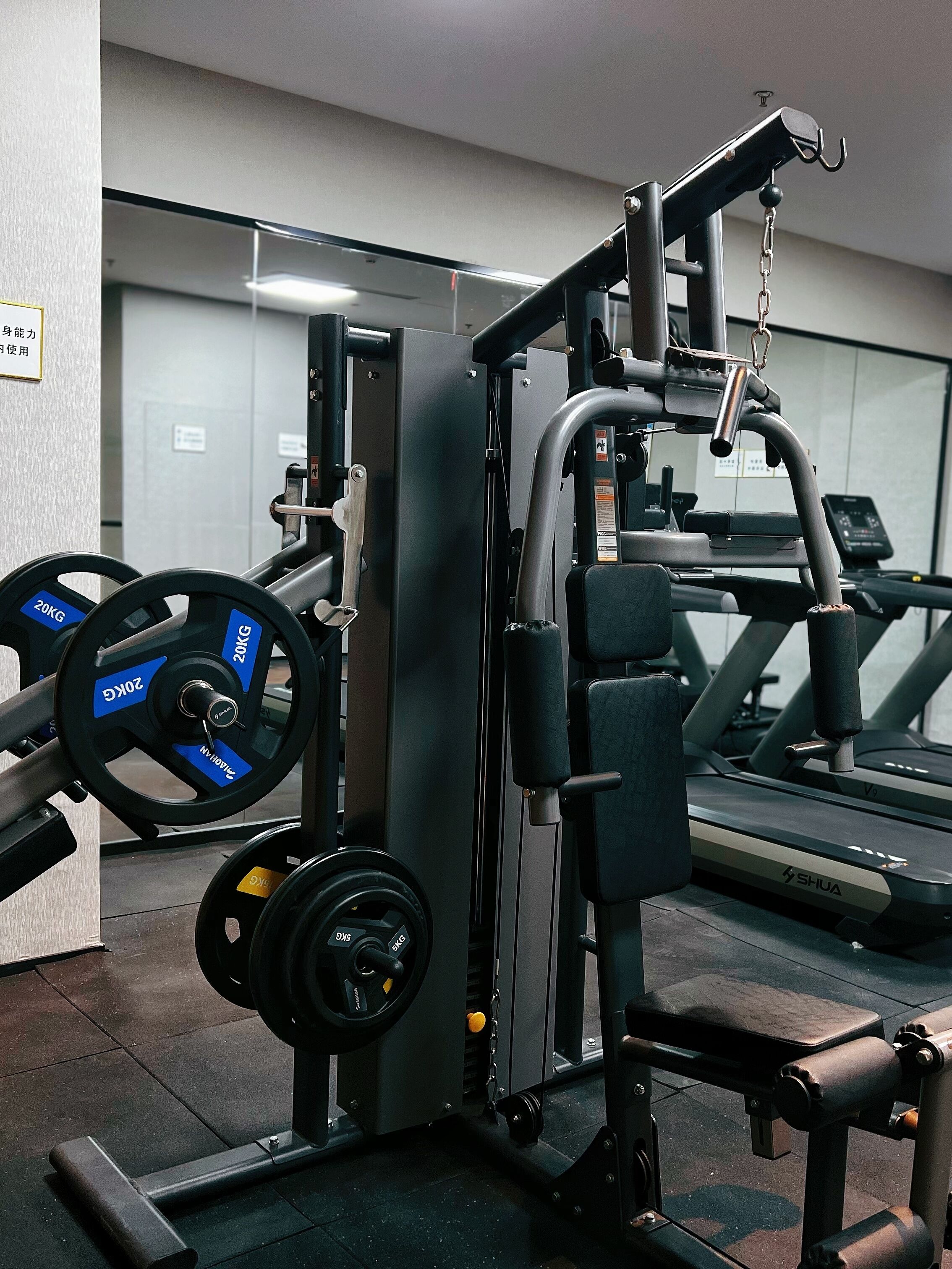 Uma academia com equipamentos de musculação, esteiras e um espelho fixado na parede.