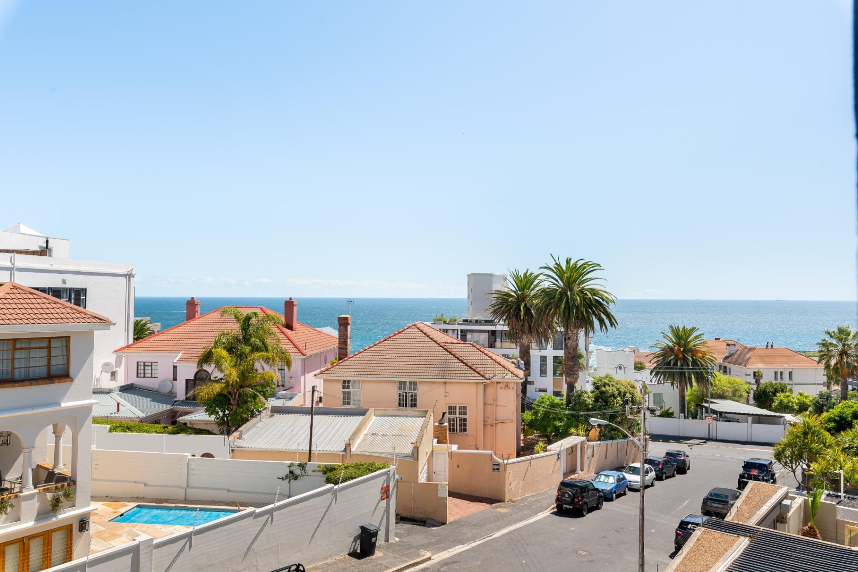 Zona residencial com casas, piscina e vista para o mar.