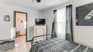 Quarto com cama, televisão, penteadeira e um banquinho estampado com padrão de zebra.