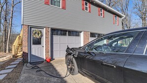 Uma casa com porta de garagem, entrada para carros e um carro estacionado em frente.