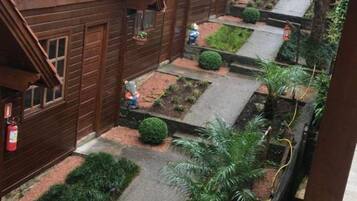 Uma fileira de casas de madeira com telhados vermelhos, um caminho estreito e pequenos jardins.