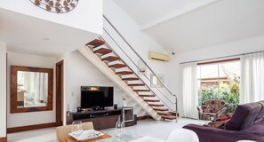 Uma sala de estar moderna com escada, televisão de tela plana e área de jantar.