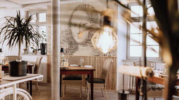 Uma sala de jantar com mesa de madeira, cadeiras e parede com um retrato.