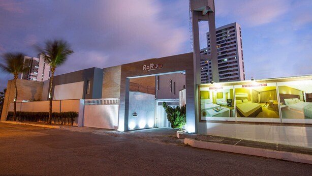 Entrada de hotel com design moderno, destacando um portão imponente e um edifício com vários andares.