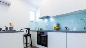 Cozinha moderna com armários brancos, forno preto e painel de azulejos azul.