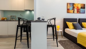 Um apartamento moderno com cozinha, sala de jantar e cama com roupa de cama amarela.