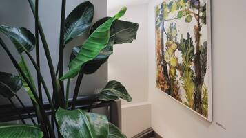 Um corredor com uma planta grande e um quadro na parede.