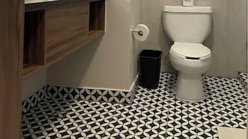 Um banheiro com vaso sanitário, pia com espelho e porta-toalhas.