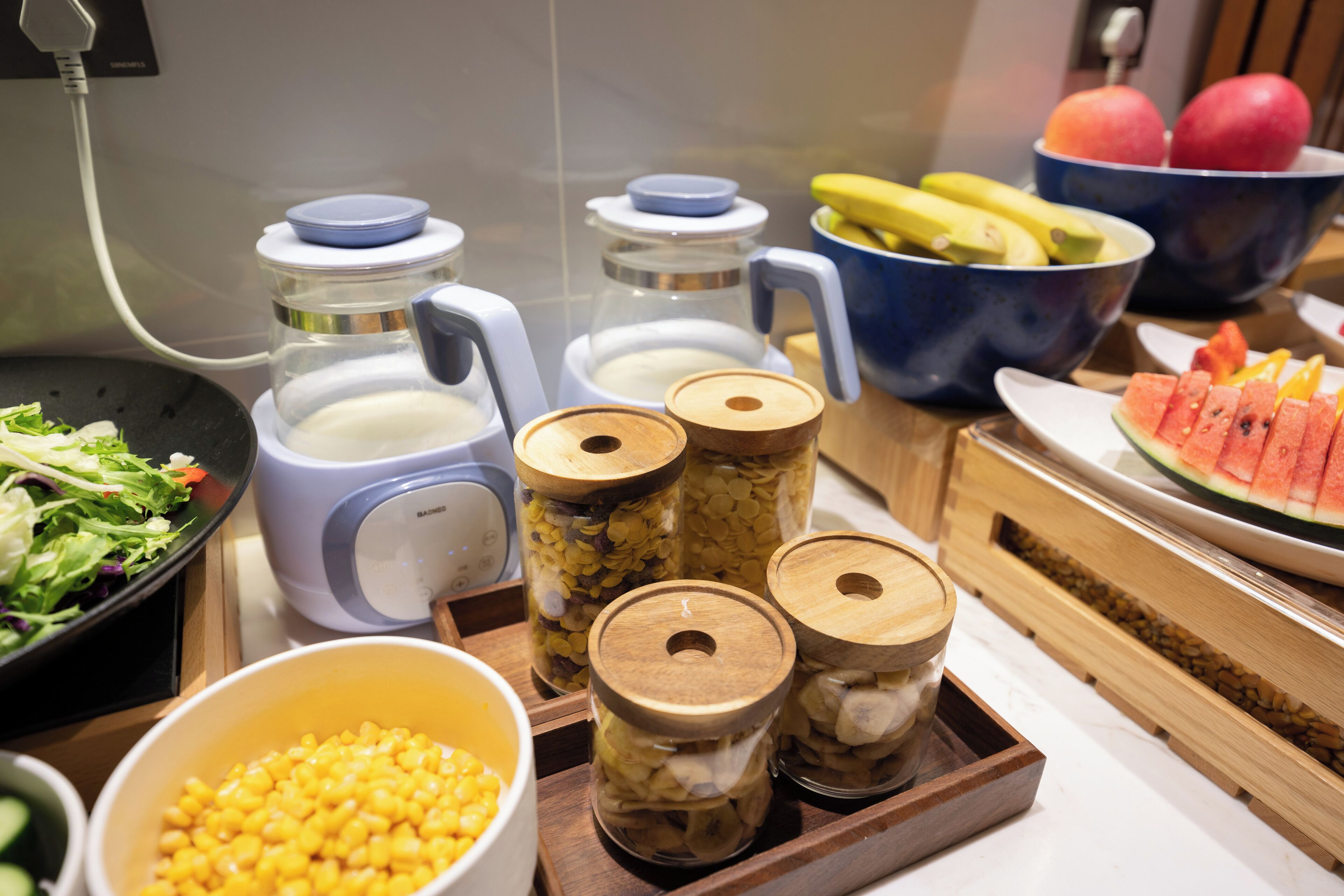 Buffet com diversos alimentos, incluindo milho, frutas e saladas.