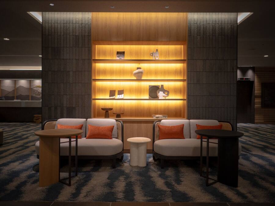 Um hall moderno com dois sofás, uma mesinha e uma estante com objetos decorativos.