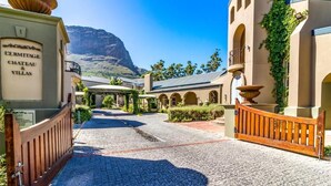 Um pátio com um caminho de pedras que leva a um portão com a placa 'LERMITAGE CHATEAU & VILLAS'.