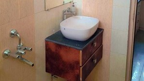 Casa de banho com lavatório branco, espelho e chuveiro.