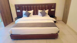 Uma cama de casal com cabeceira de madeira, duas mesas de cabeceira e uma paleta de cores neutras.