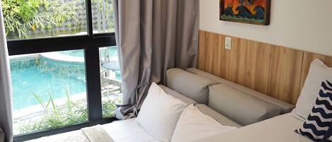 Quarto de hotel com cama, vista para uma piscina e um quadro na parede.
