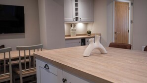 Uma cozinha moderna com armários brancos, bancada de madeira e um vaso branco singular.
