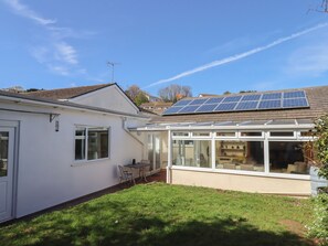Uma casa com telhado solar, conservatório e um pequeno jardim.