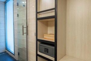 Um banheiro moderno com box de vidro, toucador de madeira com fechadura embutida e piso revestido com azulejos claros.