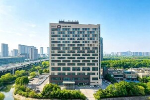 Hotel de vários andares com design moderno, apresentando um pátio central com vegetação e uma área de estacionamento.
