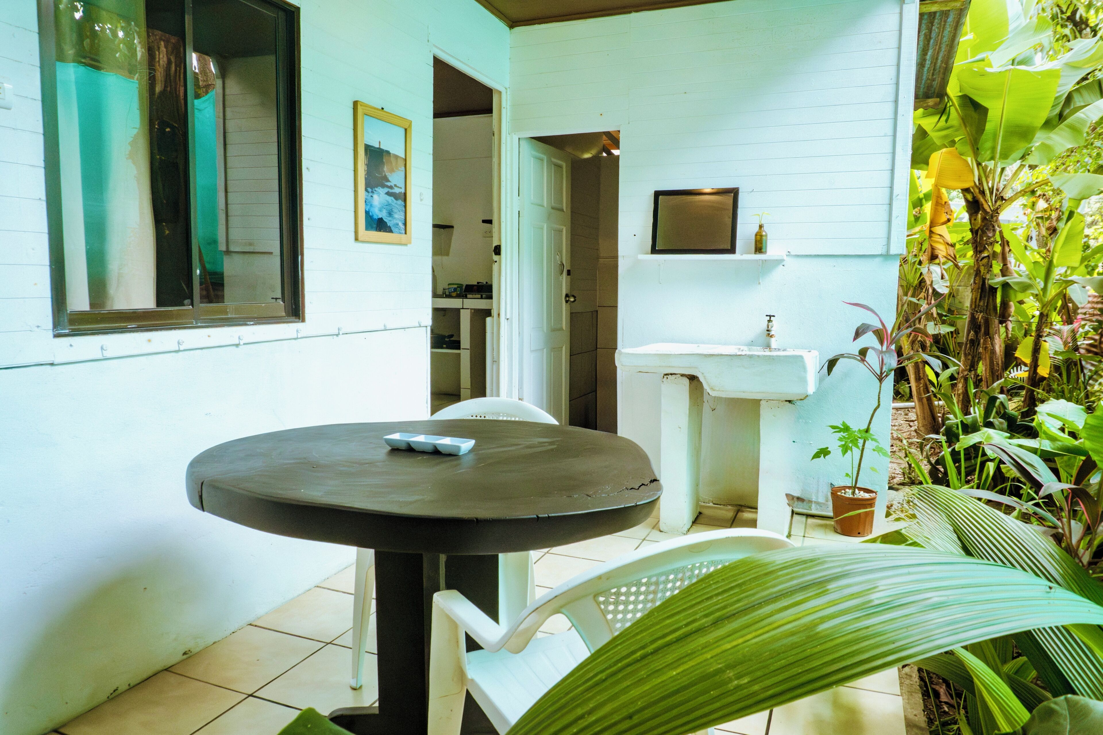 Quarto com uma mesa redonda e cadeiras, pia e janela com cortinas.