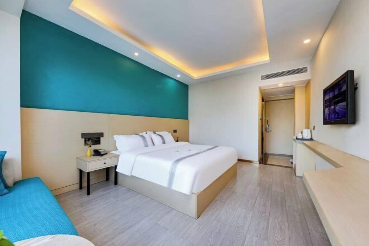 Quarto de hotel moderno com cama, mesa de cabeceira e televisão.