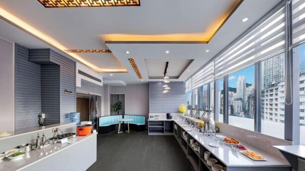 Cozinha moderna com bancada comprida, eletrodomésticos embutidos e vista para a cidade através de grandes janelas.