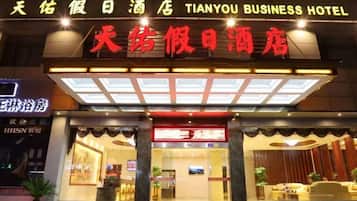 Um hotel com uma placa grande indicando 'TIANYOU BUSINESS HOTEL' e outra placa em idioma diferente.