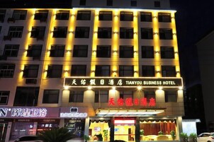 Um hotel com vários andares, fachada visível e sinalização iluminada.