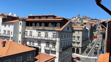 Vista da rua de uma cidade com edifícios históricos, céu azul claro e uma bandeira em um mastro.