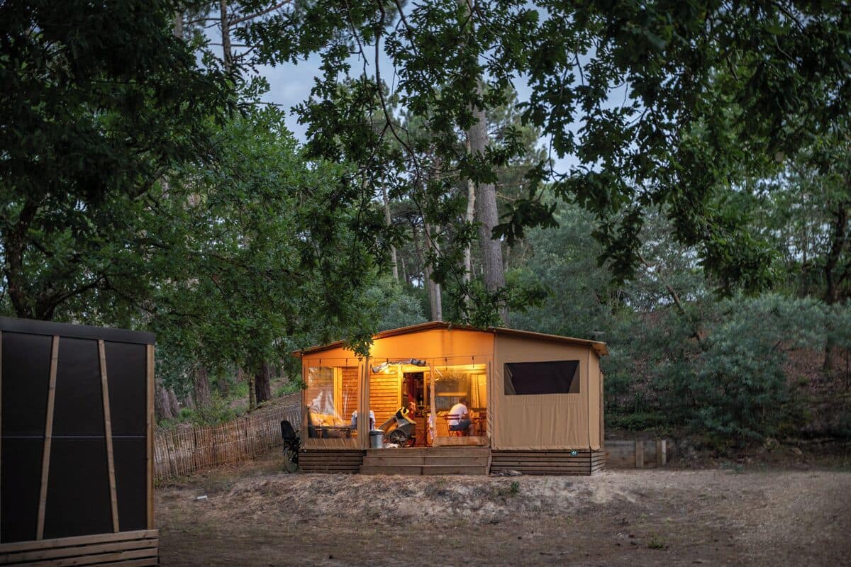 Uma cabana pequena e térrea com varanda, rodeada por árvores.