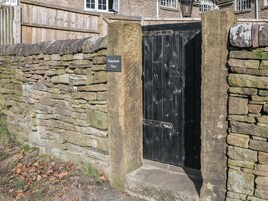Mural de pedra com um portão preto e uma placa com a inscrição 'Oakenbank Barn'.