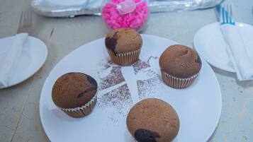 Um prato com quatro muffins sobre uma mesa com toalha de mesa estampada.