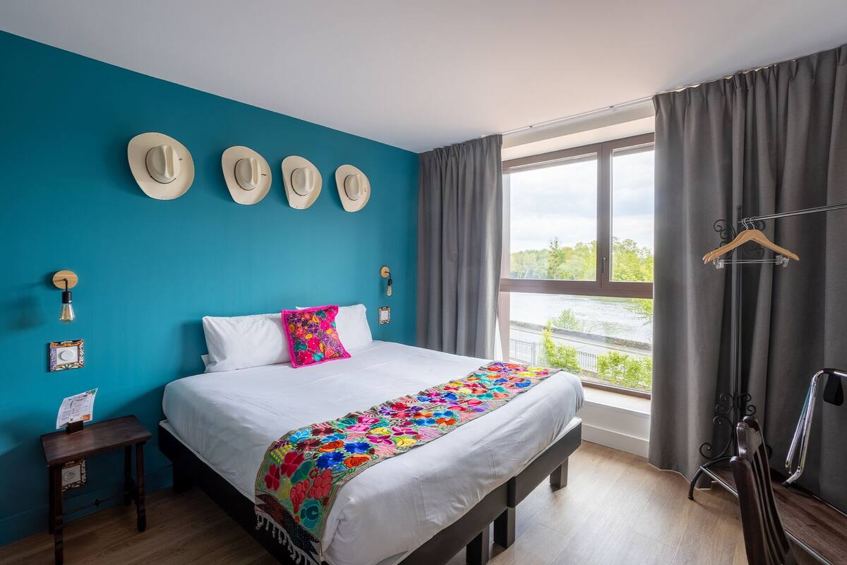 Quarto de hotel com uma cama grande, vista para o exterior e uma janela com cortinas.