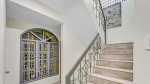 Escadaria com corrimão decorativo e janela com grade de metal.