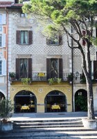 Um edifício com um restaurante chamado "Ristorante del Battello", com fachada de pedra, janelas em arco e mesas ao ar livre.