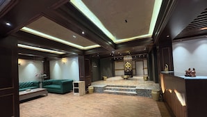 Um hall amplo com um sofá verde, um balcão de recepção e uma fonte decorativa.