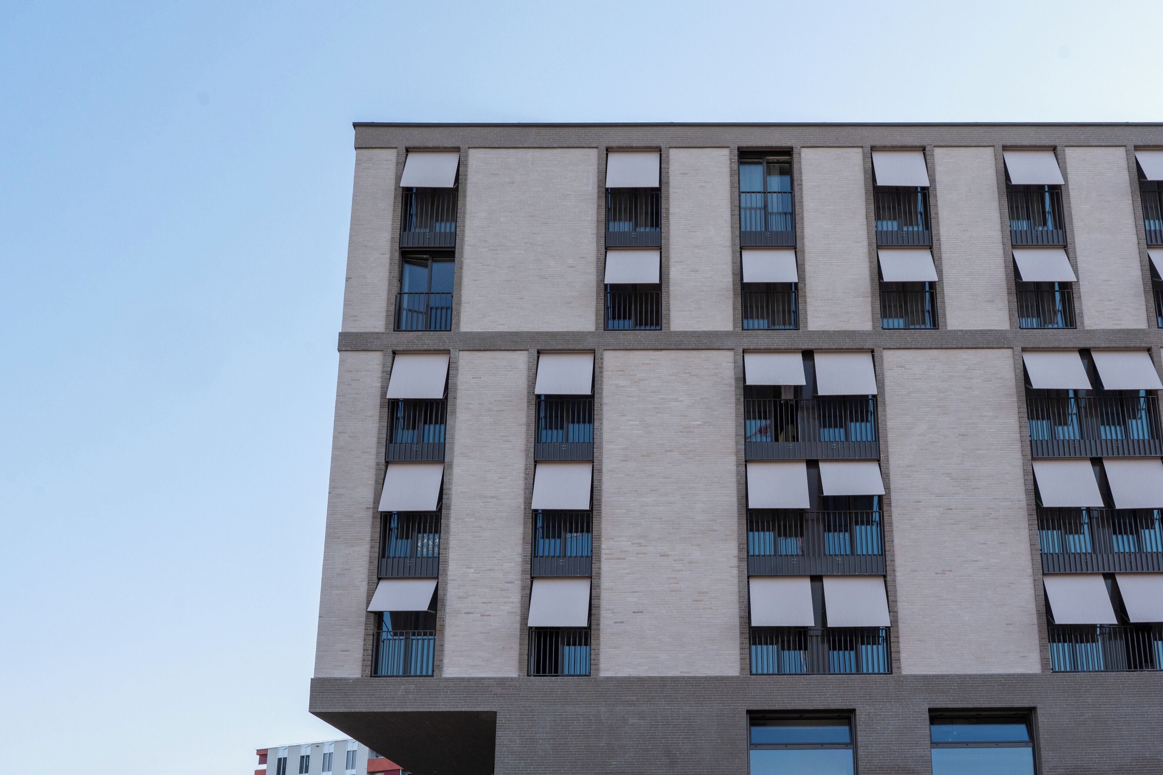 Um edifício de vários andares com design arquitetônico moderno, apresentando uma série de varandas e grandes janelas.