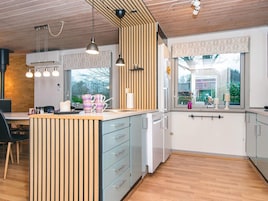 Cozinha moderna com ilha de madeira, luminárias pendentes e uma janela ampla com vista para o exterior.
