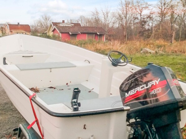 Um barco motorizado branco com motor de popa Mercury, um leme e uma corda de segurança vermelha.