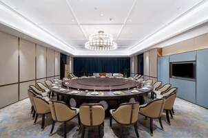 Uma sala de conferências com uma mesa redonda, cadeiras e um candelabro.