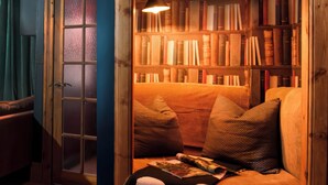 Um quarto aconchegante com uma estante de madeira, um espaço de estar acolchoado e uma porta que dá para outro cômodo.