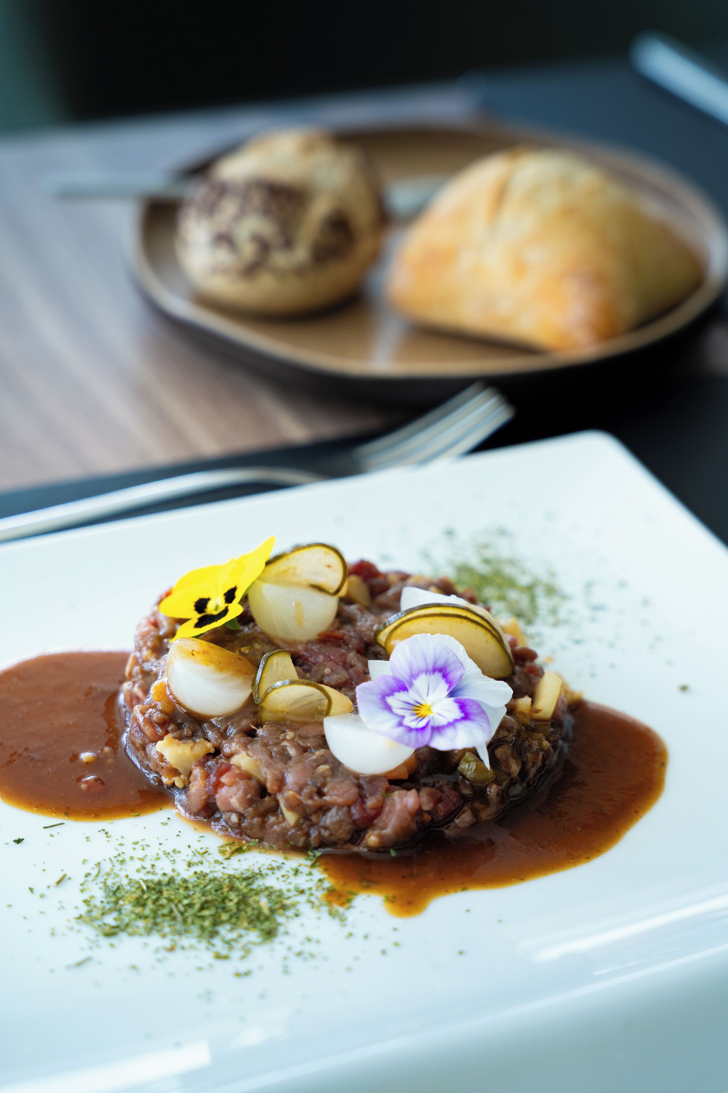 Prato de comida com molho, decorado com ervas e flores.
