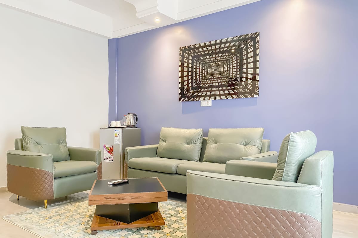 Uma sala de estar com sofá, mesa de centro e geladeira.