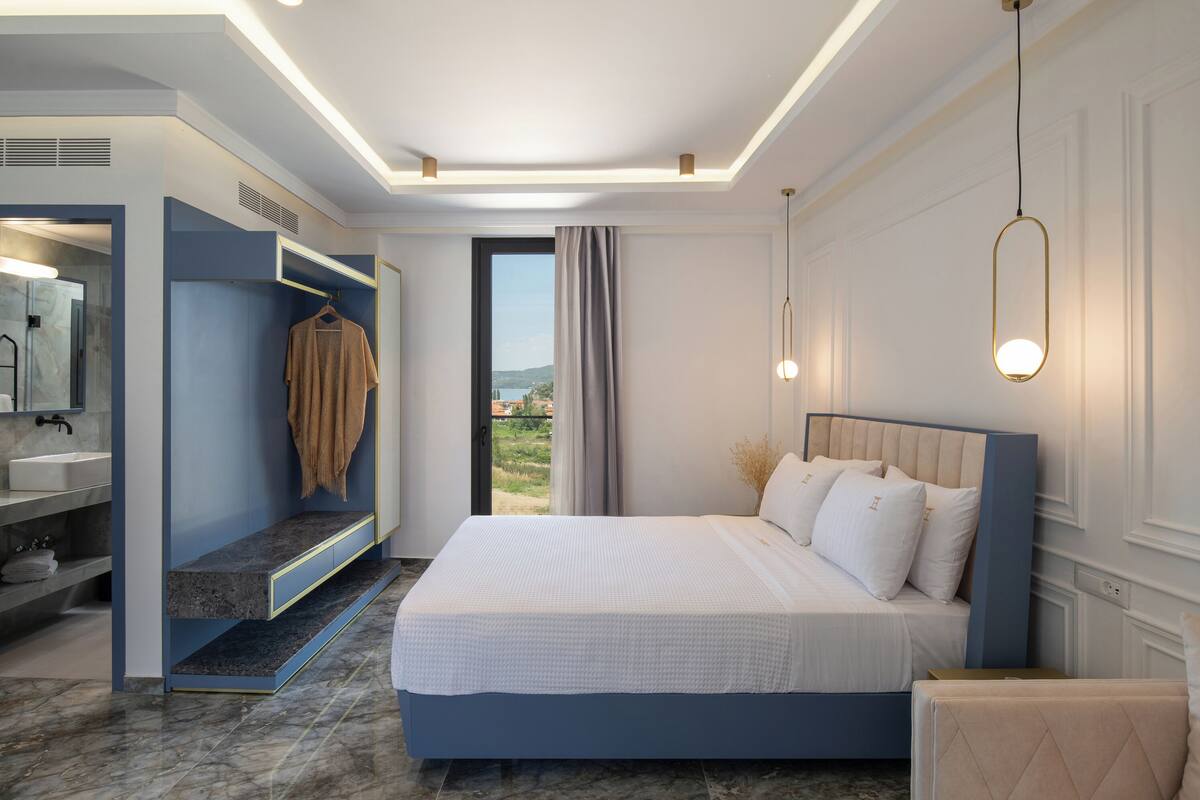 Quarto de hotel moderno com cama grande, armário embutido e banheiro com piso de mármore.