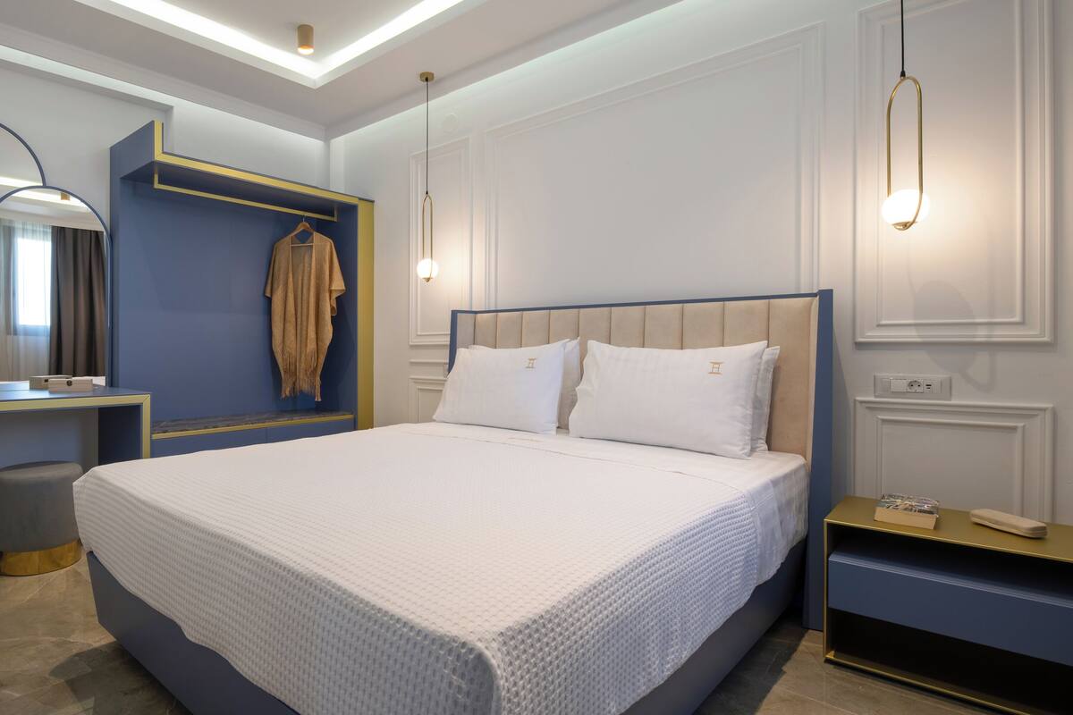 Quarto moderno com cama grande, mesa de cabeceira, guarda-roupa e luminária pendente.